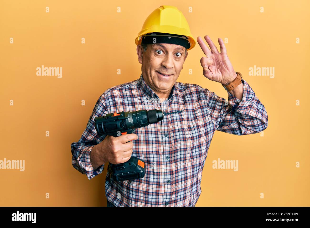 Handsome senior man with grey hair holding screwdriver wearing hardhat ...