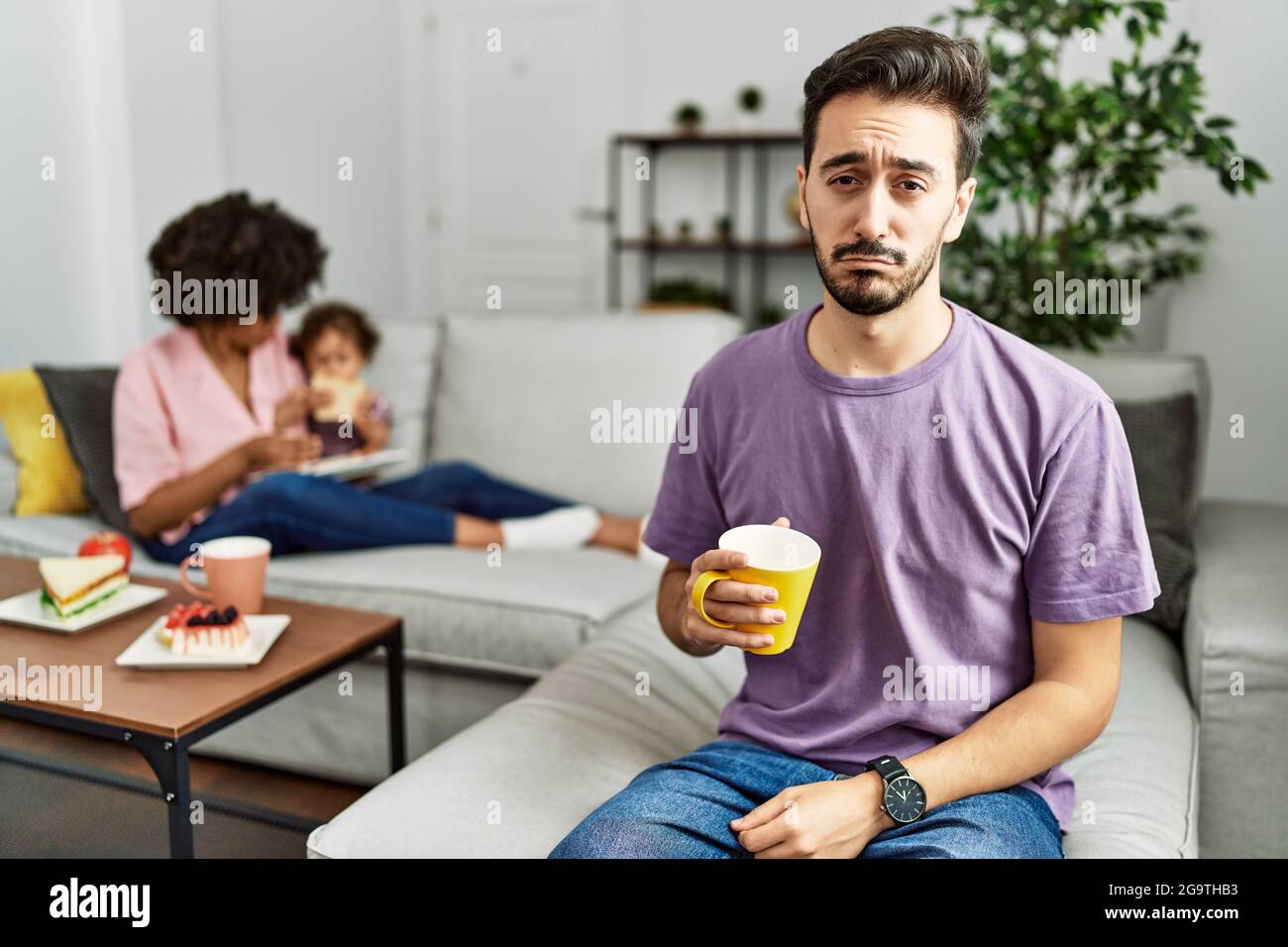 Hispanic father of interracial family drinking a cup coffee depressed ...