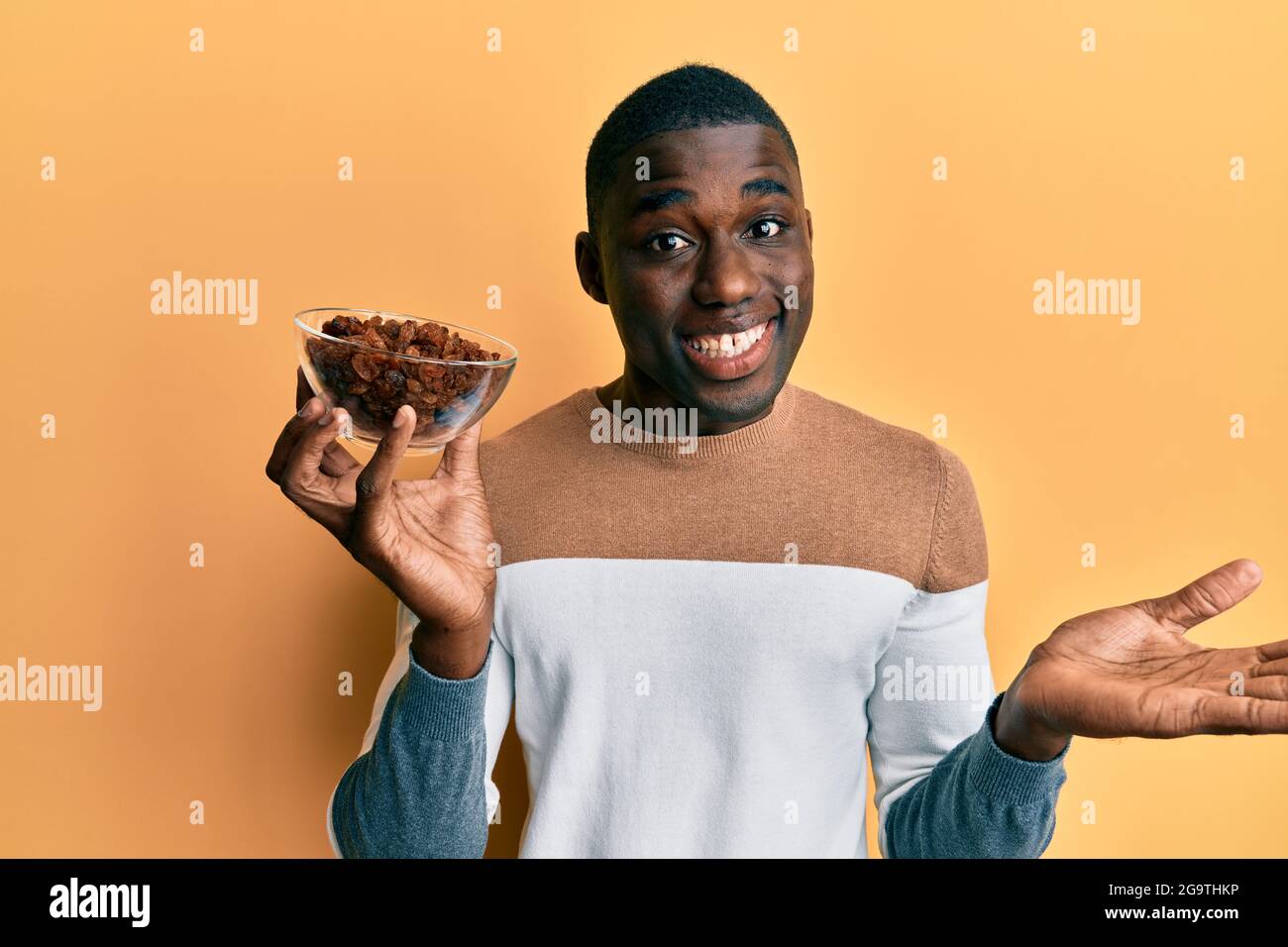 Young african american man holding bowl with raisins celebrating ...