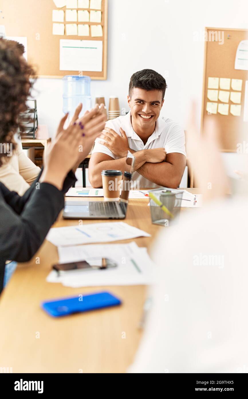 Group of young business workers smiling and clapping to partner at the ...
