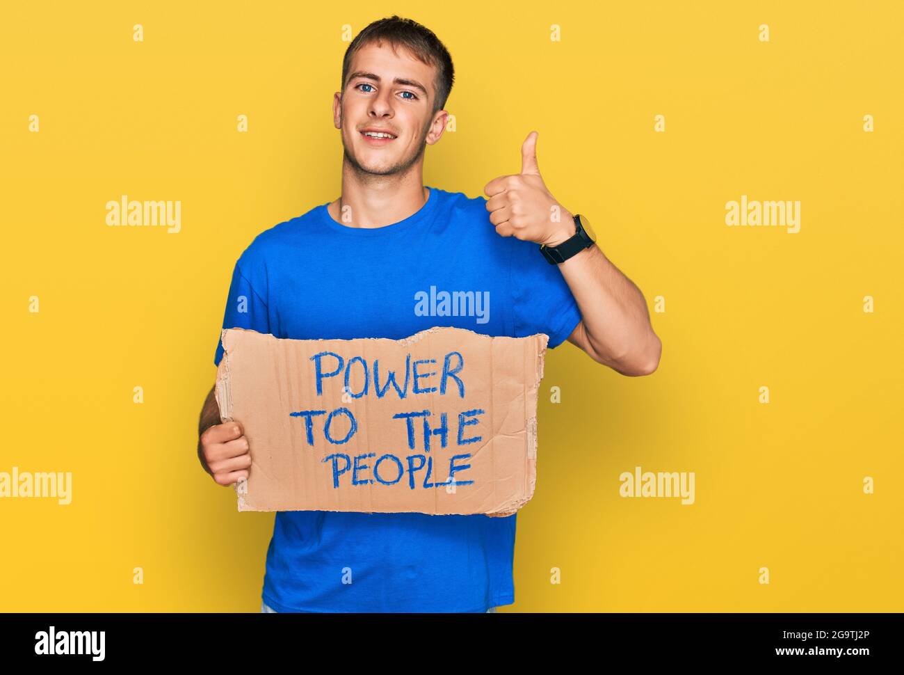Young blond man holding power to the people banner smiling happy and ...