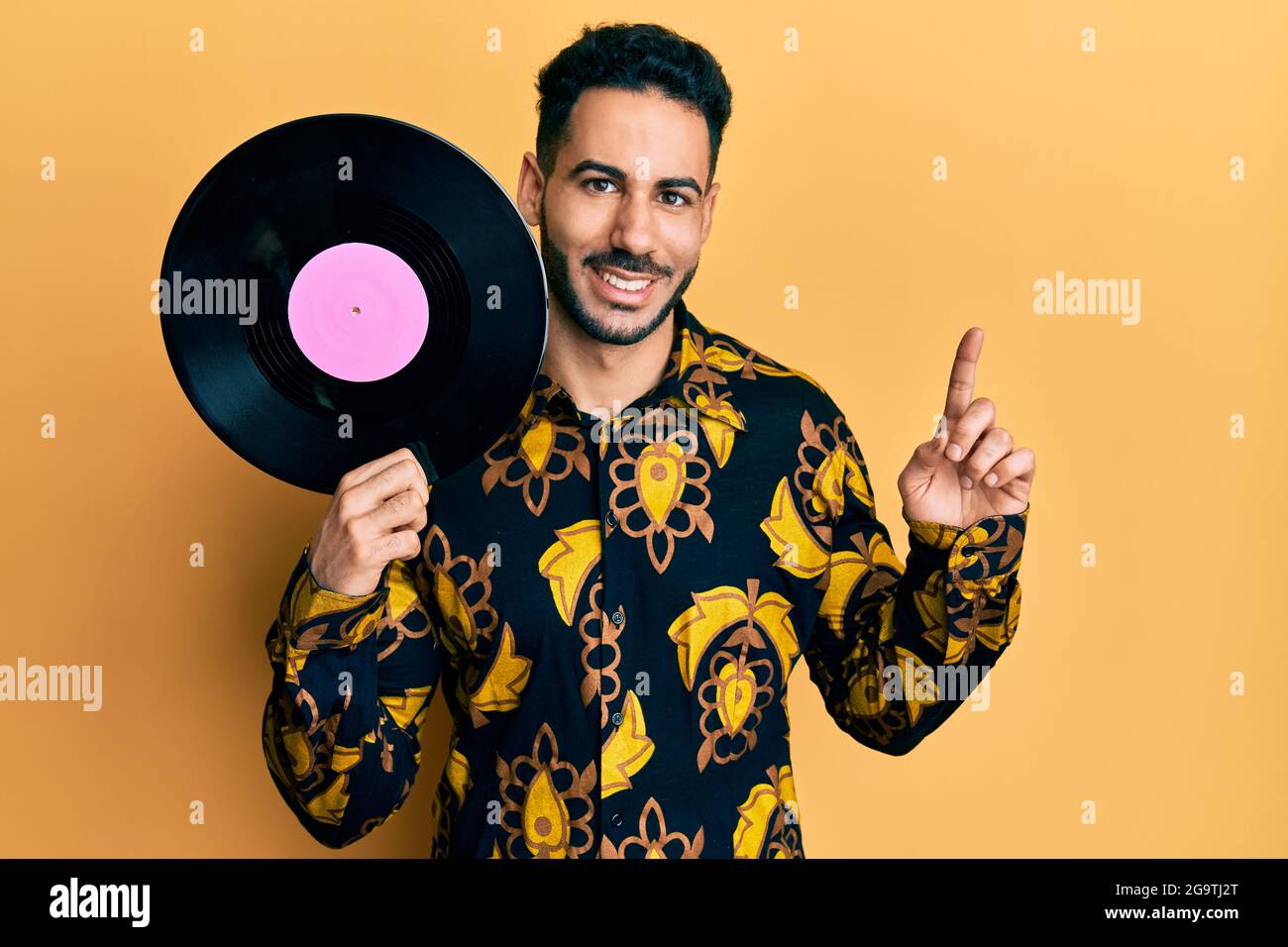 Young hispanic man holding vinyl disc smiling with an idea or question ...