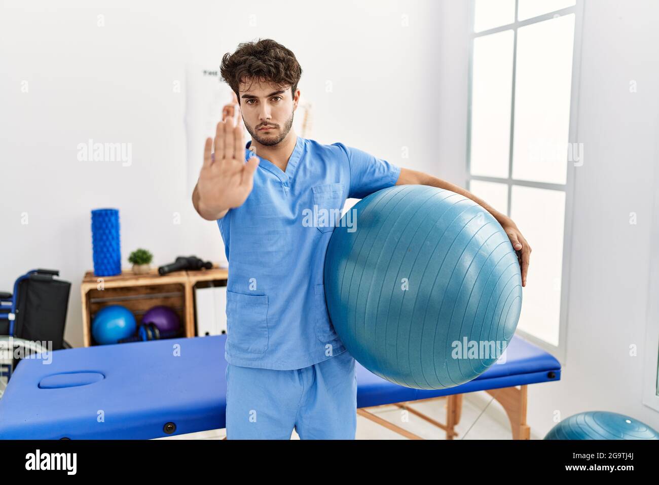 Hispanic physiotherapy man working at pain recovery clinic with open ...