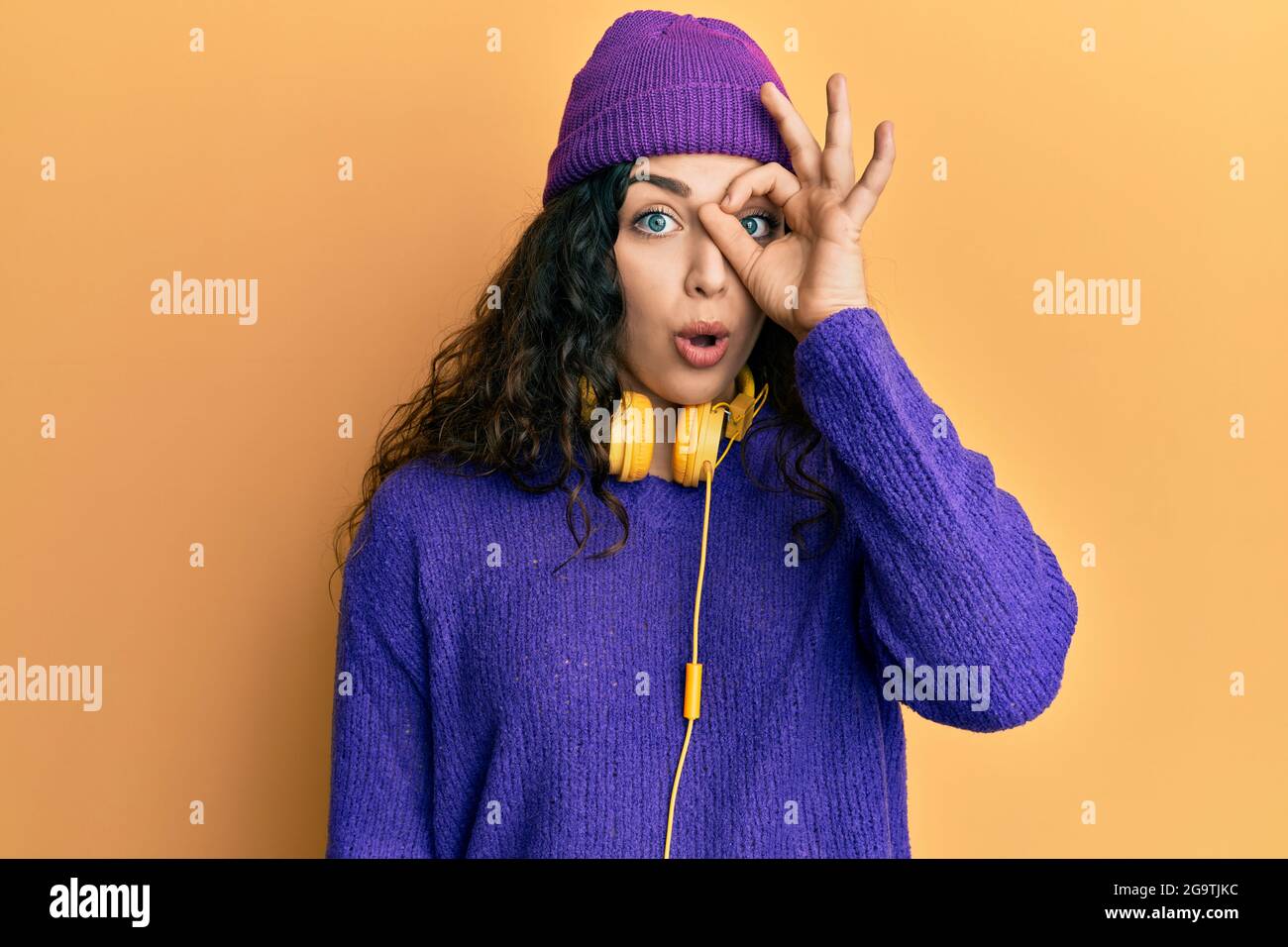 Young brunette woman with curly hair listening to music using ...