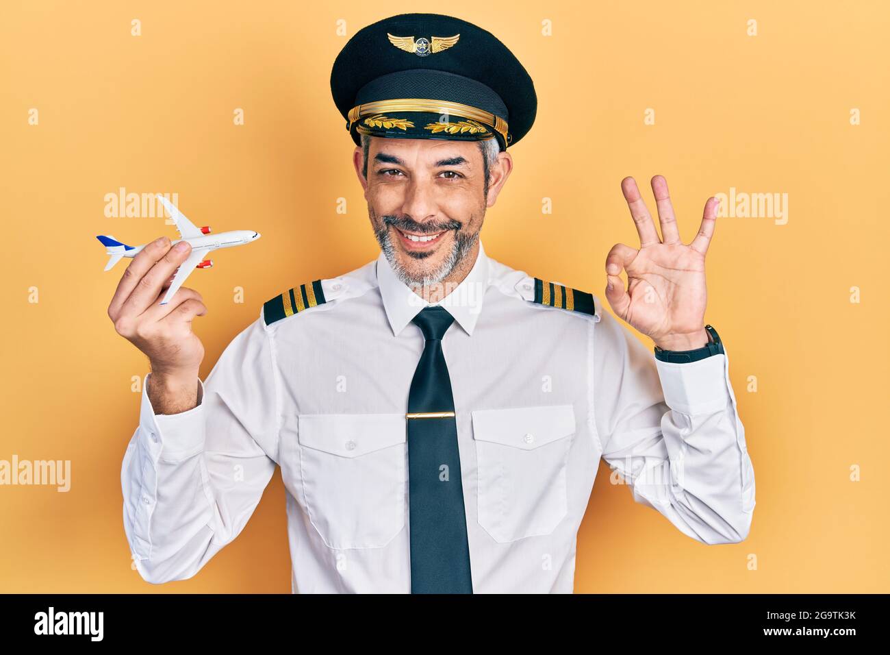 Handsome middle age man with grey hair wearing airplane pilot uniform ...