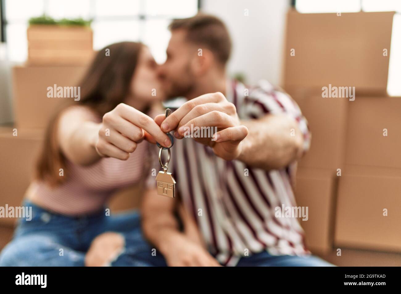 Young caucasian couple kissing and holding key of new home Stock Photo ...