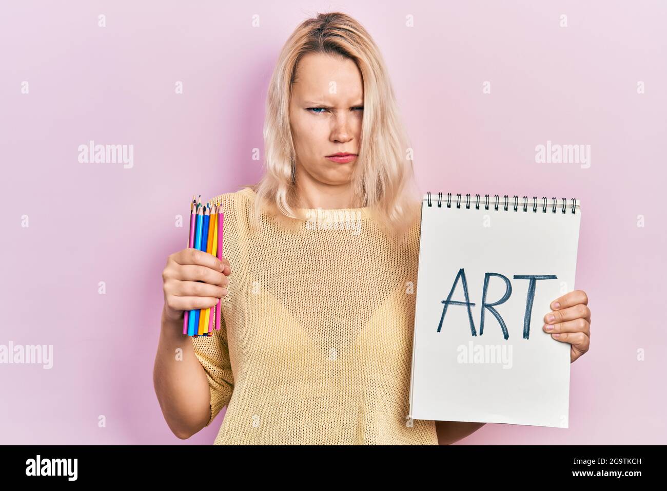 Beautiful caucasian blonde woman holding art notebook and color pencils ...