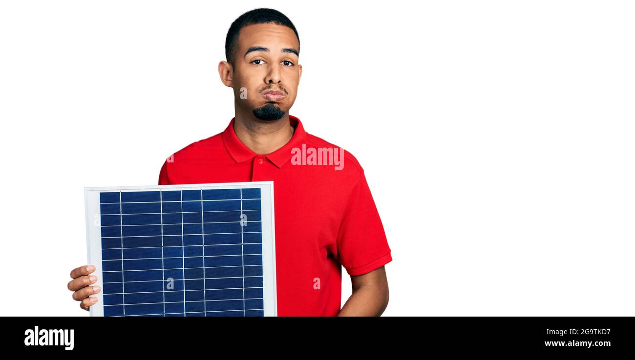 Young african american man holding photovoltaic solar panel puffing ...