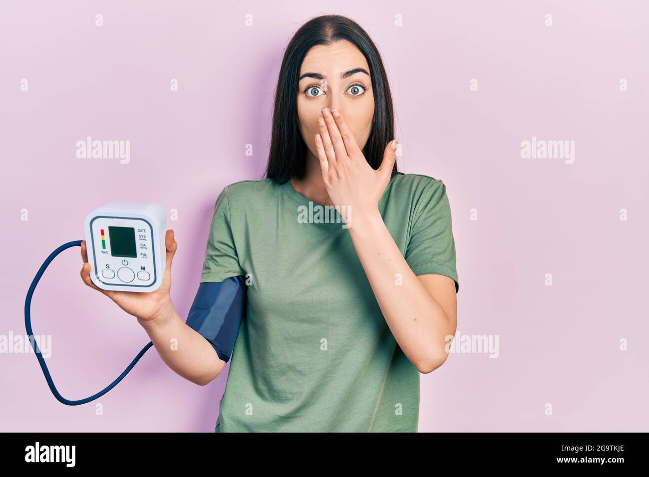 Beautiful woman with blue eyes using glucose meter covering mouth with ...