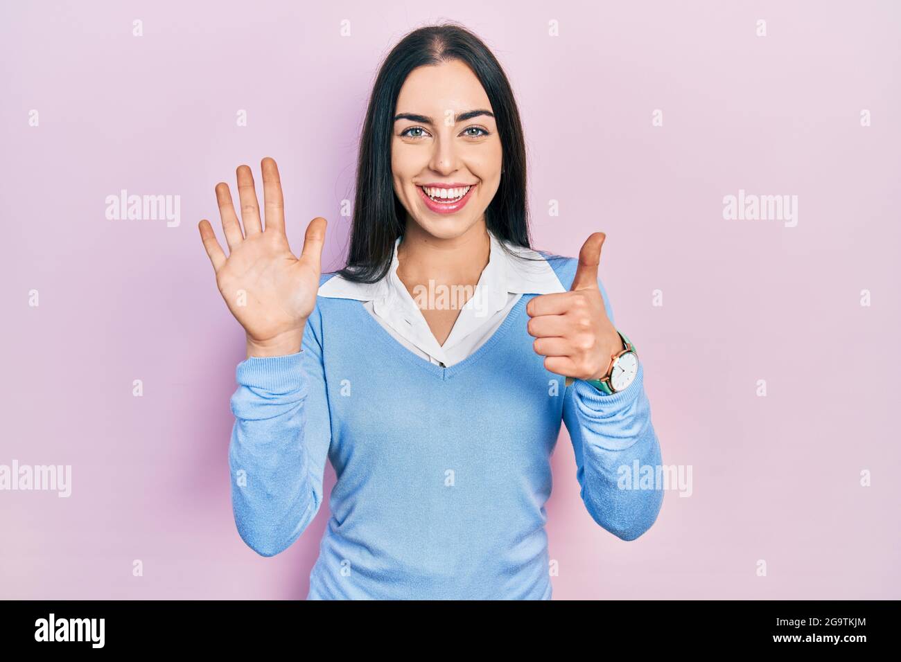 Beautiful woman with blue eyes standing over pink background showing ...