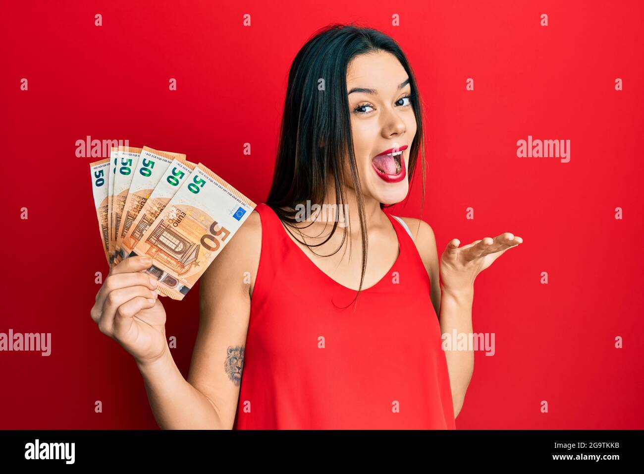 Young hispanic girl holding euro banknotes celebrating achievement with ...