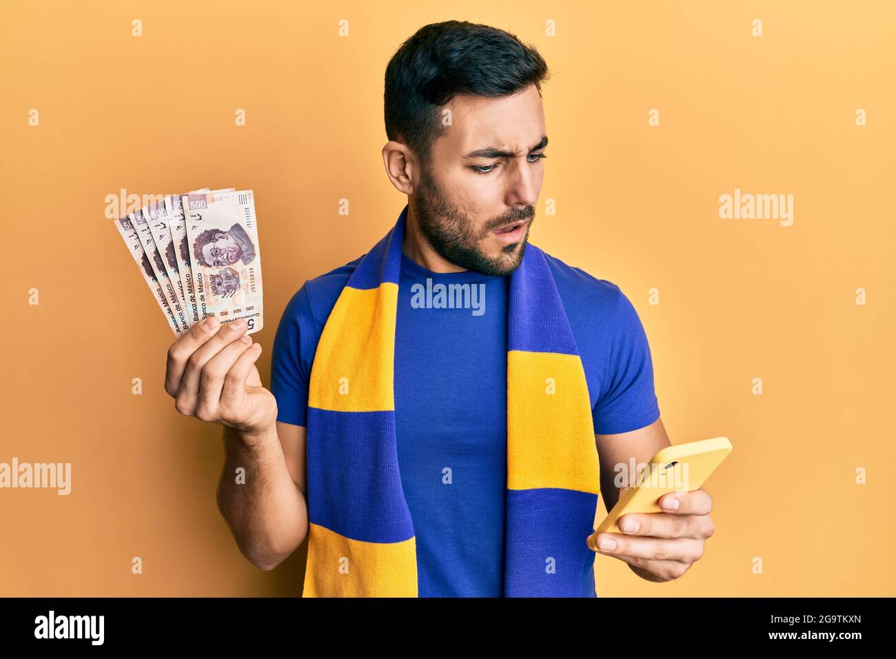 Young hispanic man football supporter using smartphone holding mexican ...