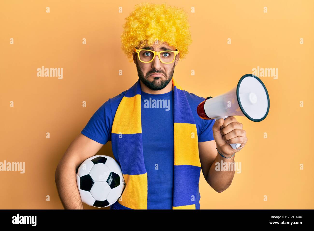 Young hispanic man football supporter holding soccer ball using ...
