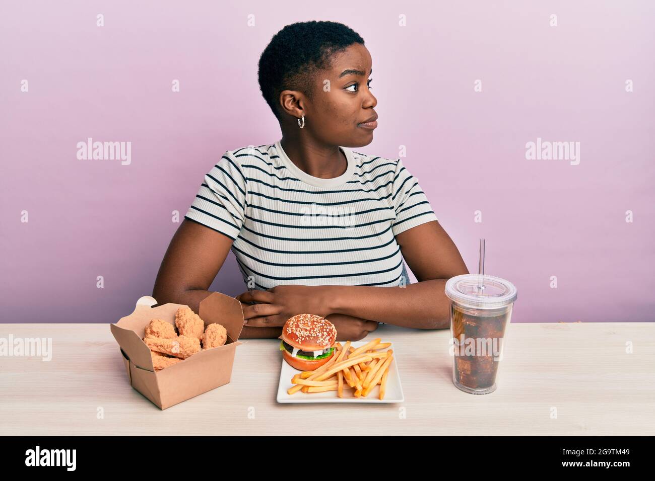 Young african american woman eating a tasty classic burger with fries ...