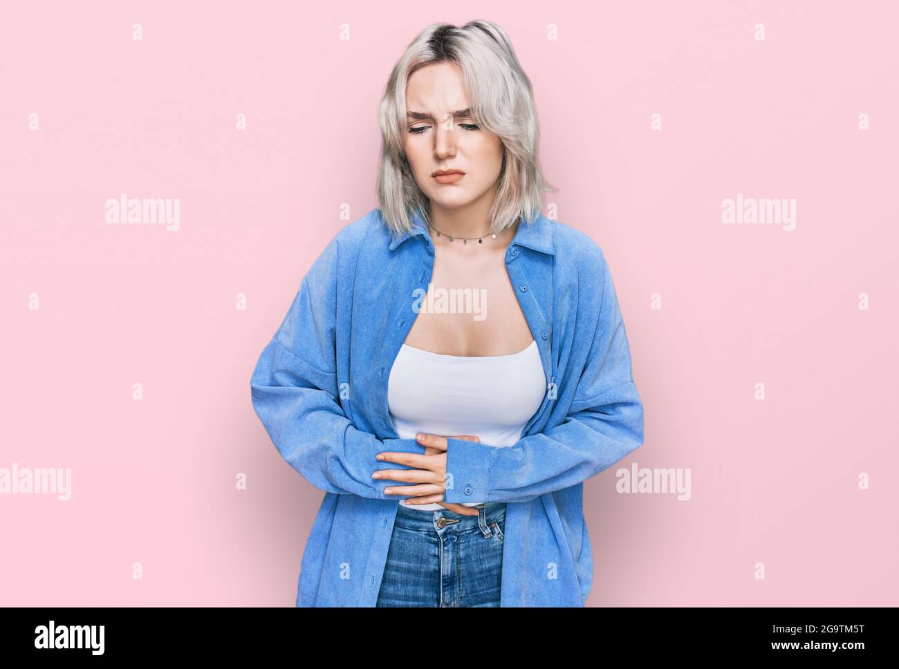 Young blonde girl wearing casual clothes with hand on stomach because ...