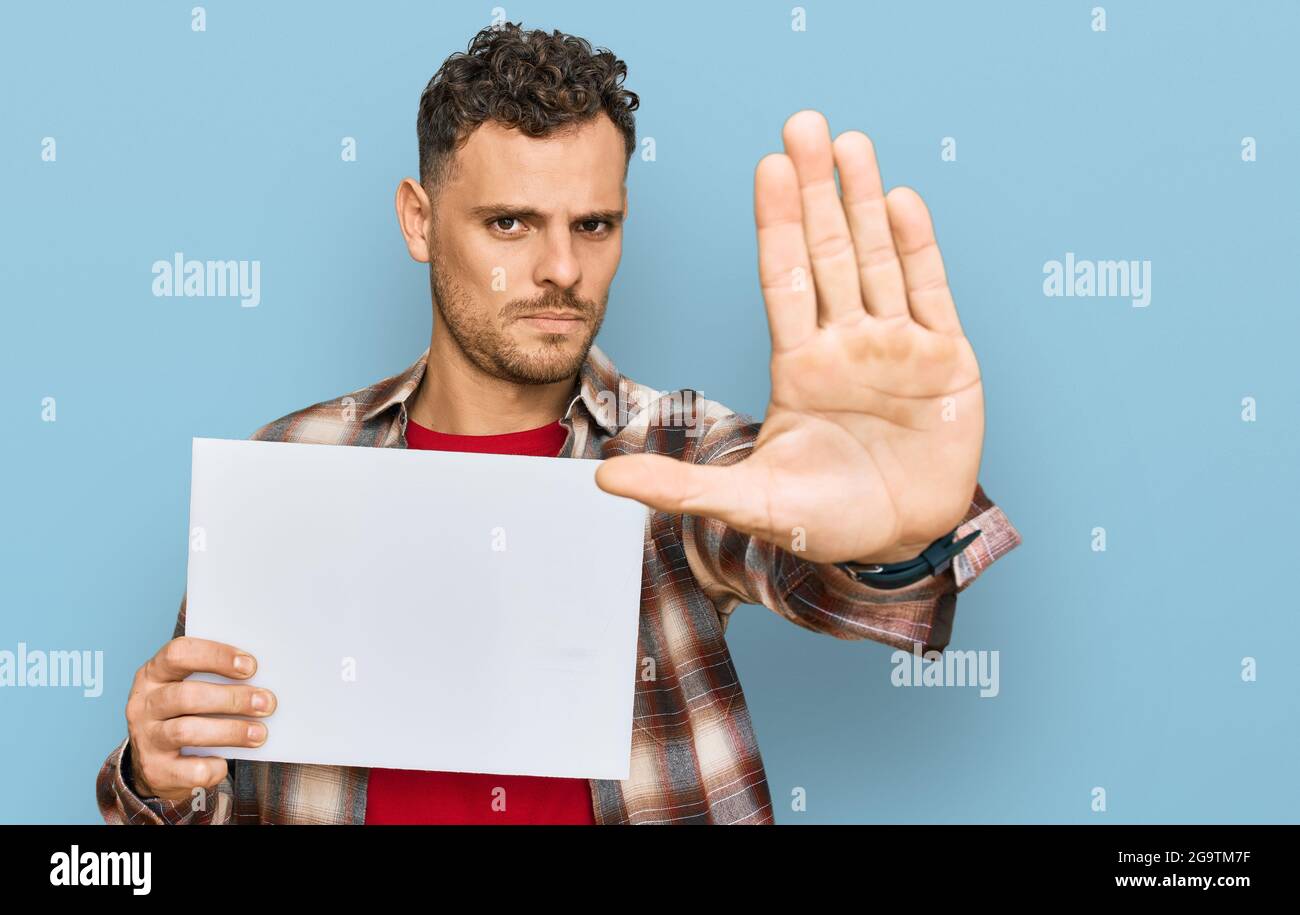 Young hispanic man holding blank empty banner with open hand doing stop ...