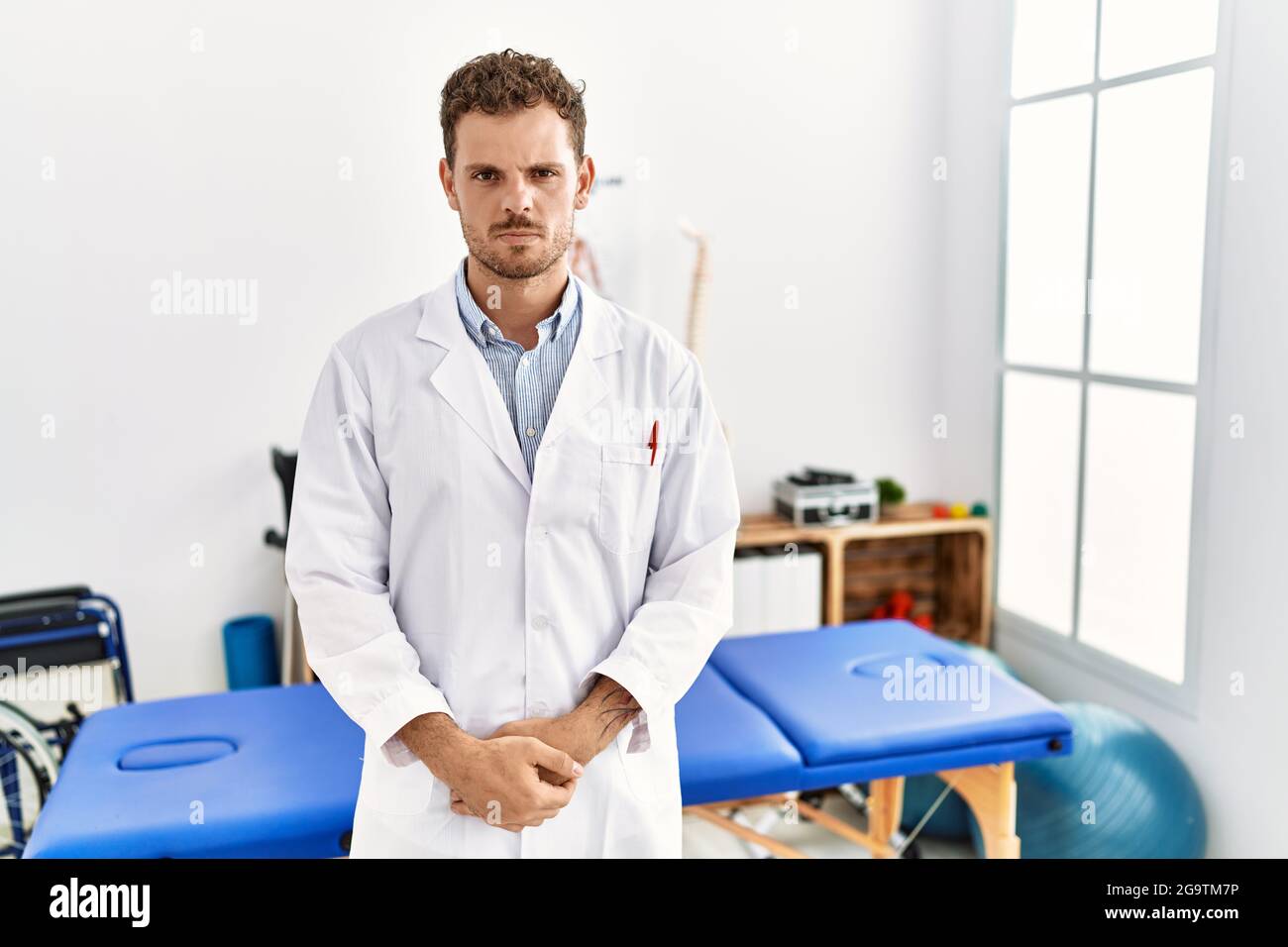 Handsome young man working at pain recovery clinic skeptic and nervous ...