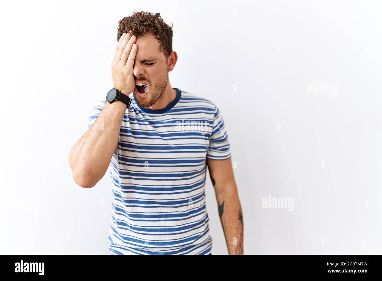 Handsome young man standing over isolated background yawning tired ...
