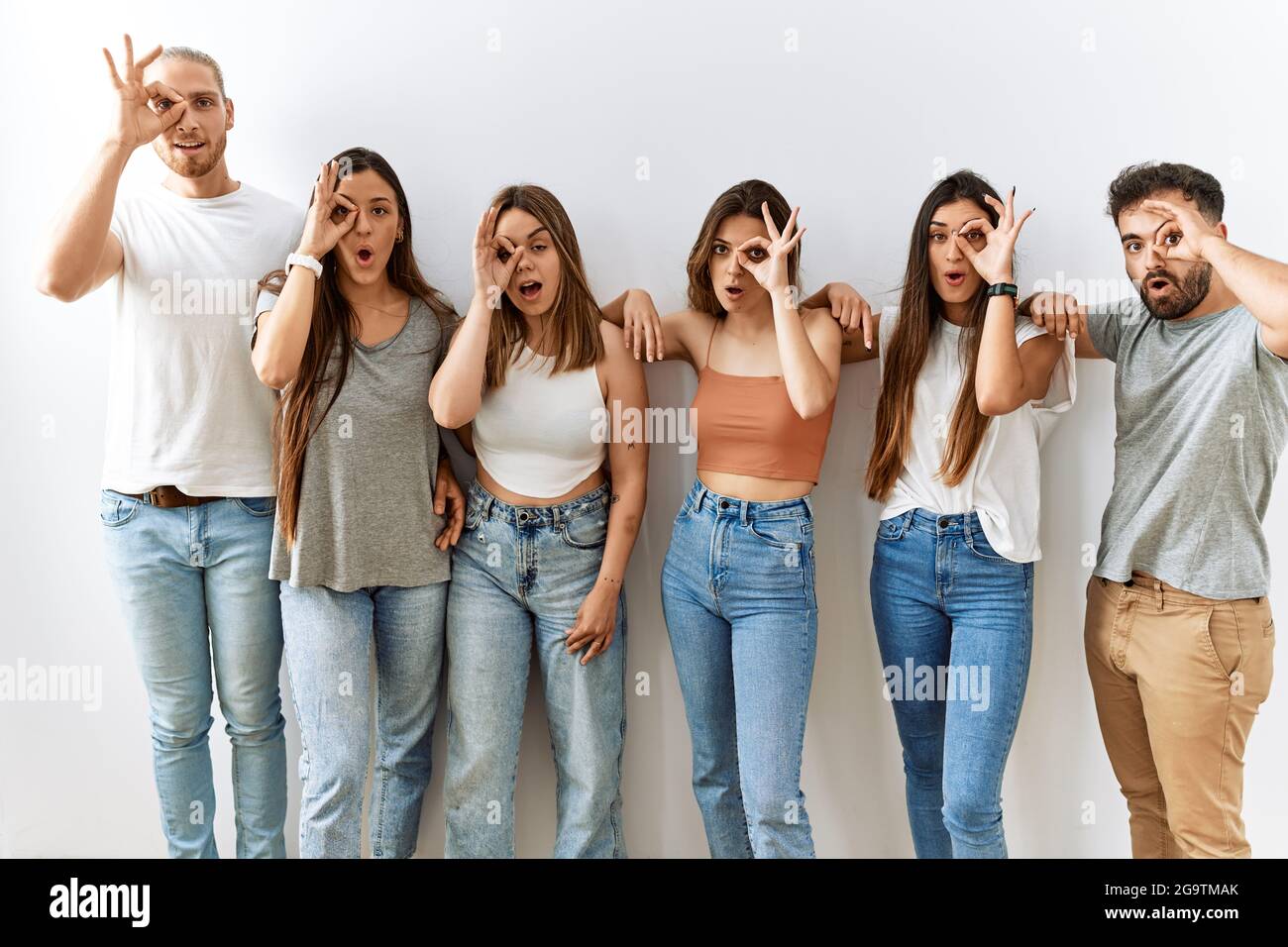 Group of young friends standing together over isolated background doing ...