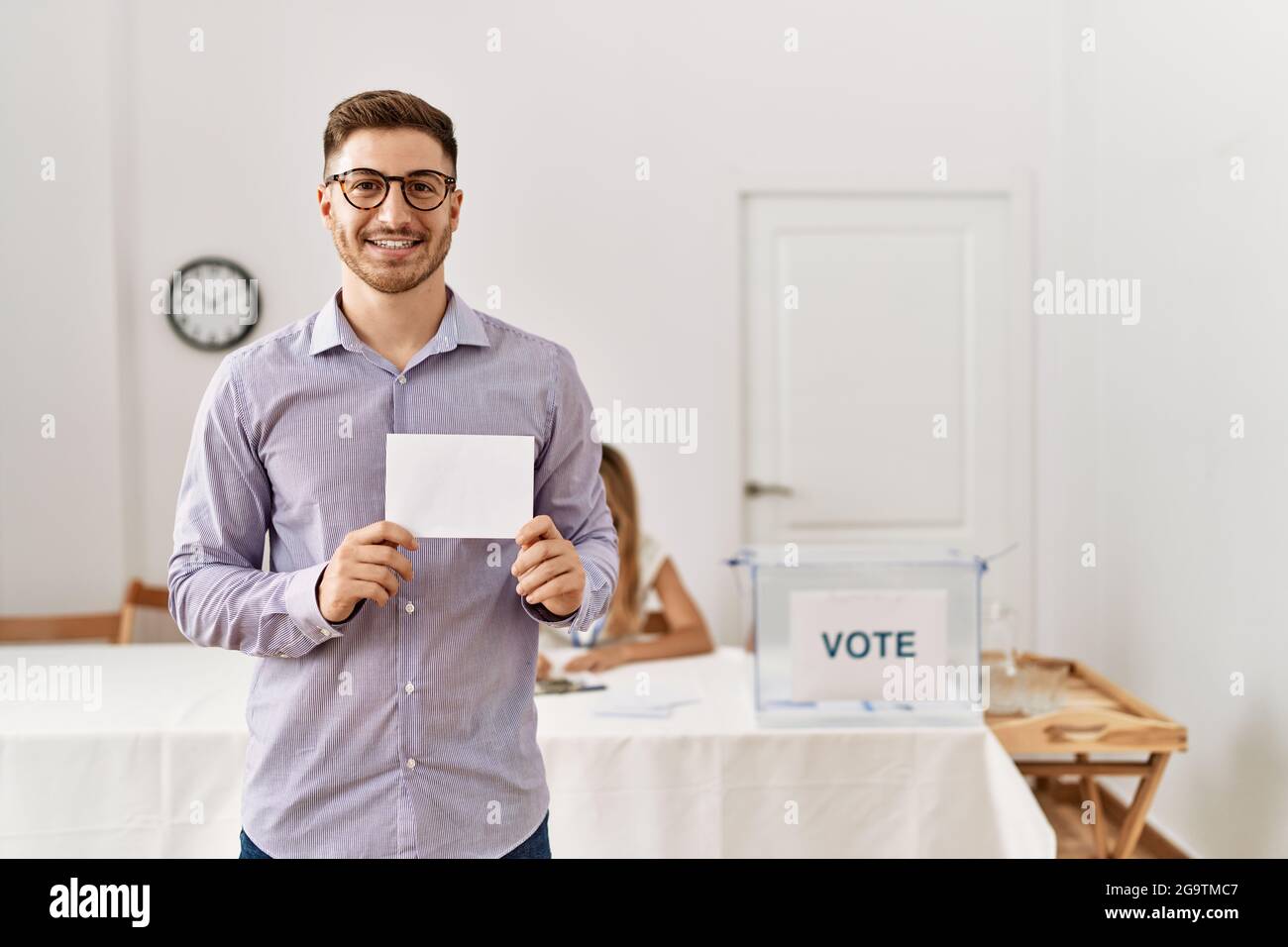 Young voter man holding blank vote standing by electoral table at vote ...