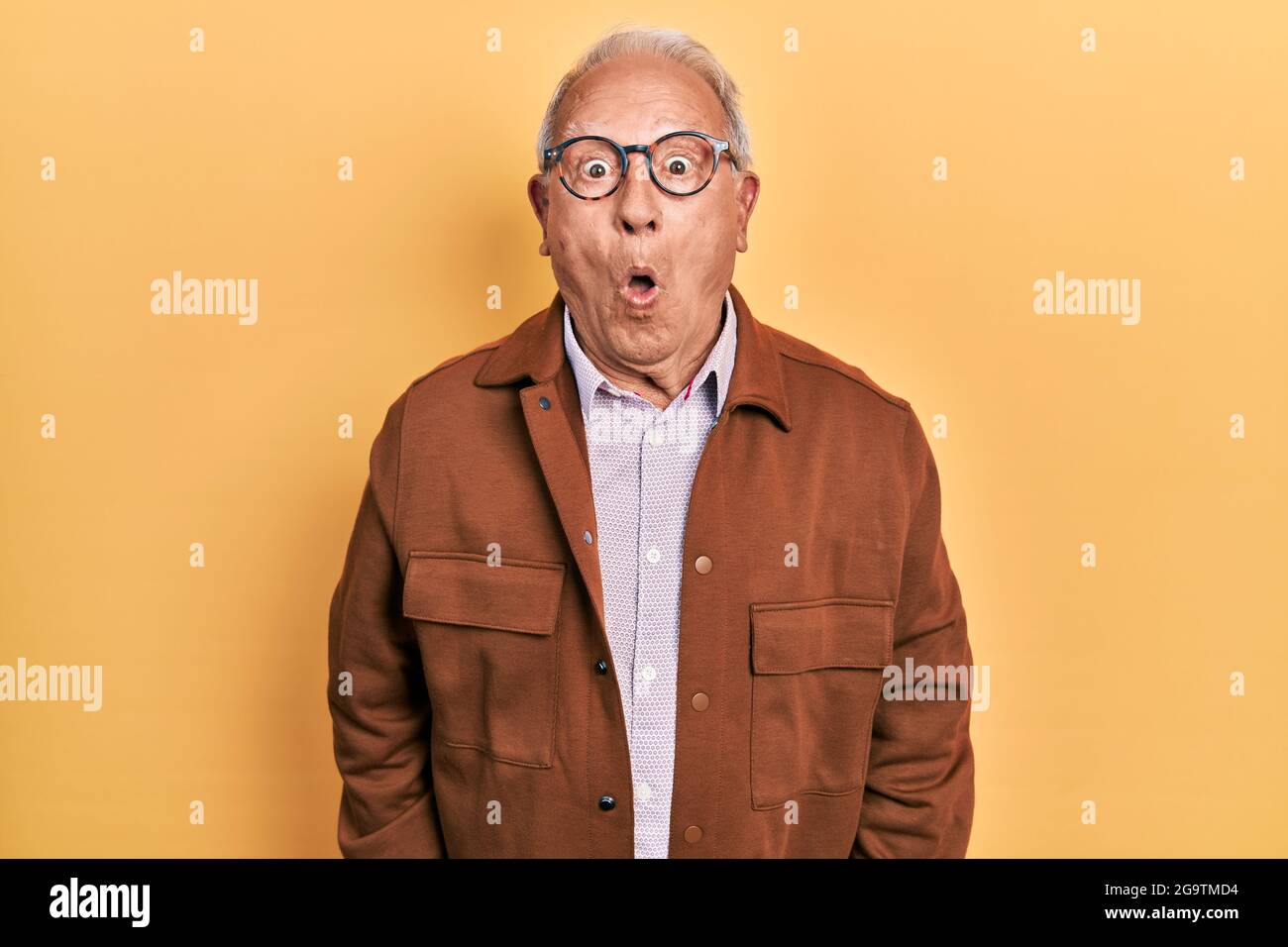 Senior man with grey hair wearing casual jacket and glasses afraid and ...