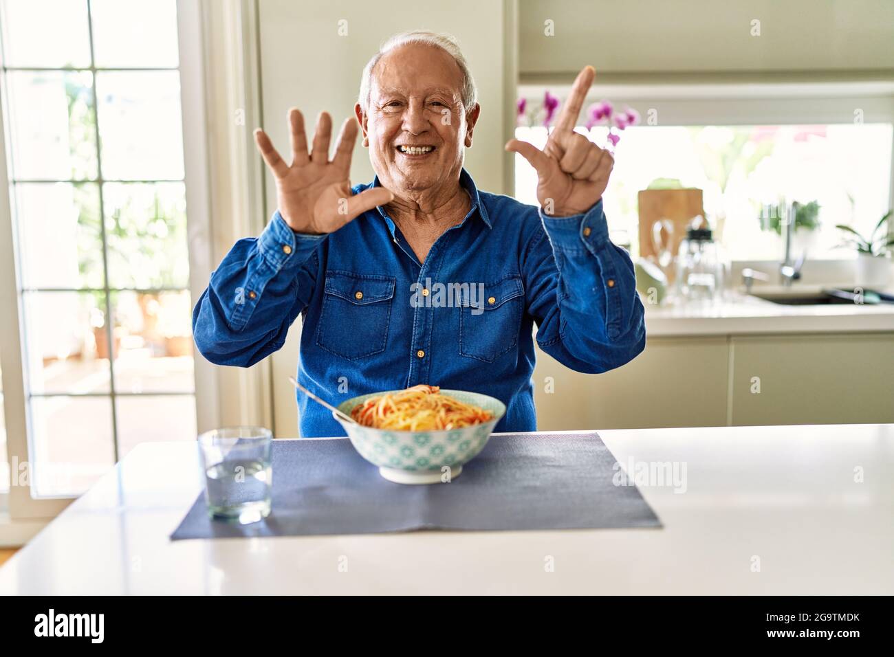 Senior man with grey hair eating pasta spaghetti at home showing and ...