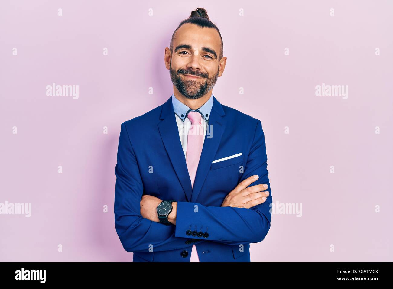 Young hispanic man wearing business suit with arms crossed gesture ...