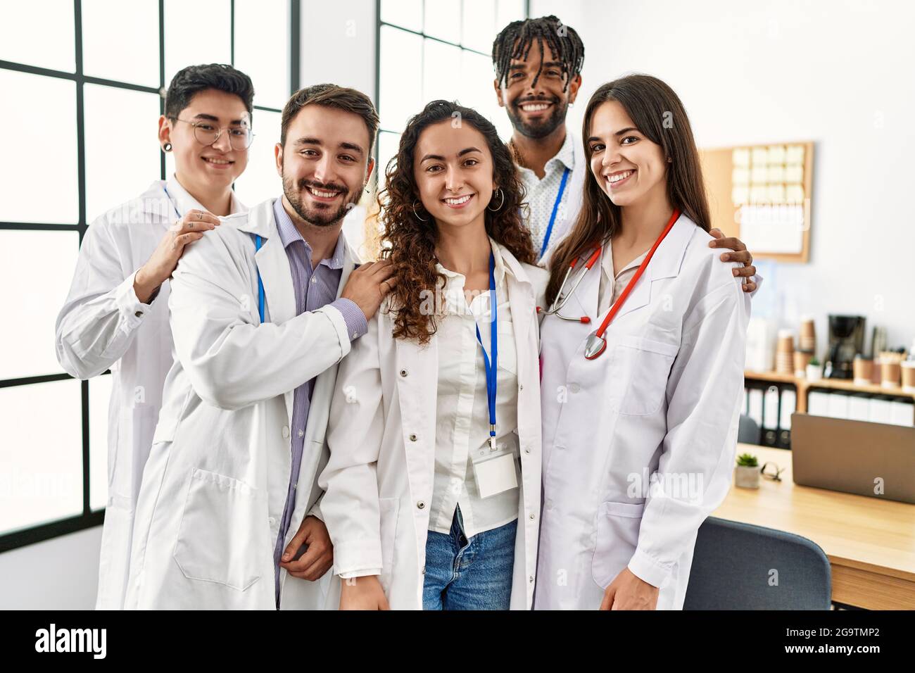 Group of young doctor smiling happy and hugging standing at the clinic ...