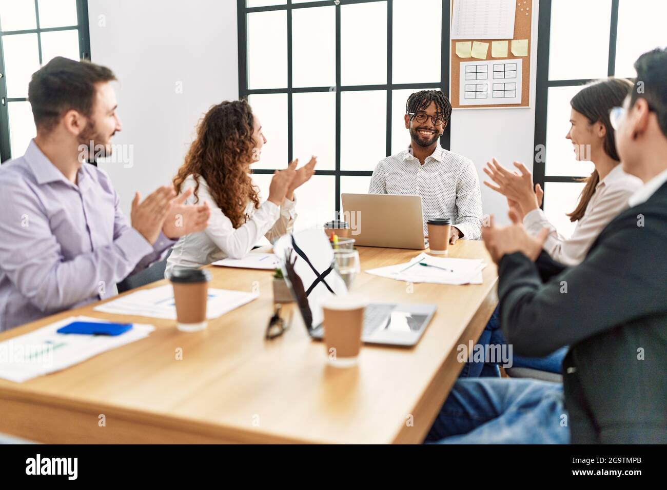 Group of business workers smiling and clapping to partner at the office ...