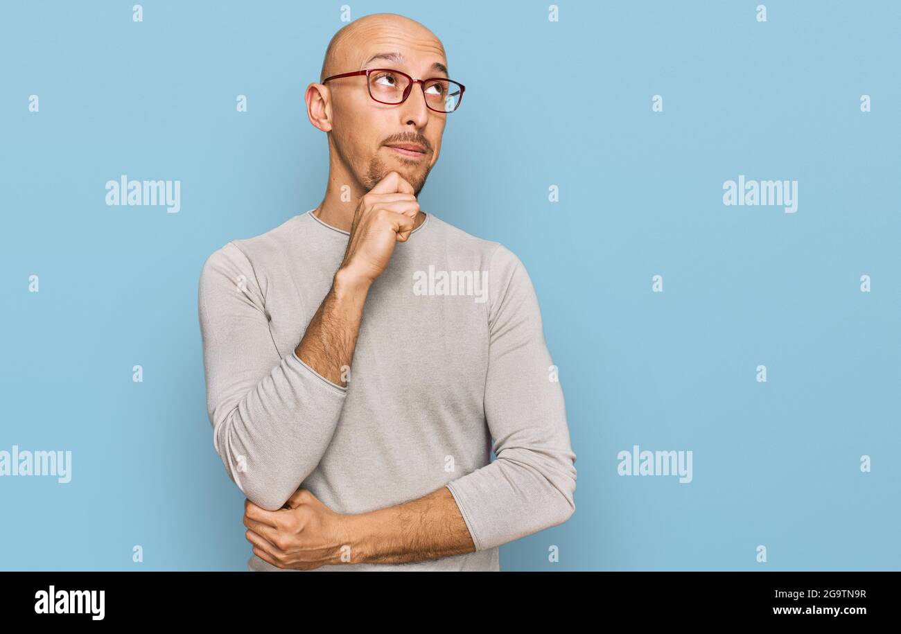 Bald man with beard wearing casual clothes and glasses with hand on ...