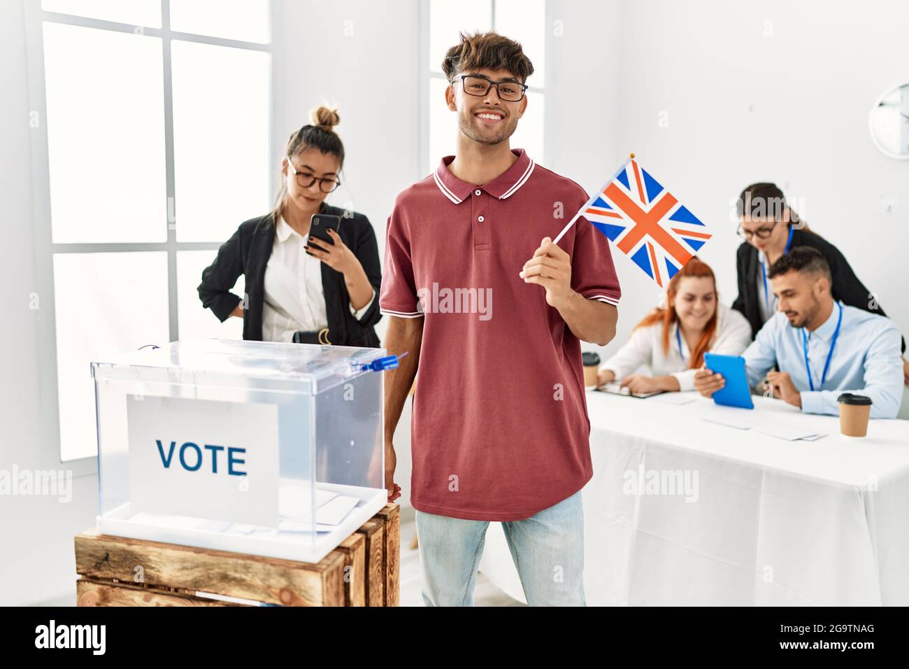 Young british voter man smiling happy holding uk flag standing at vote ...