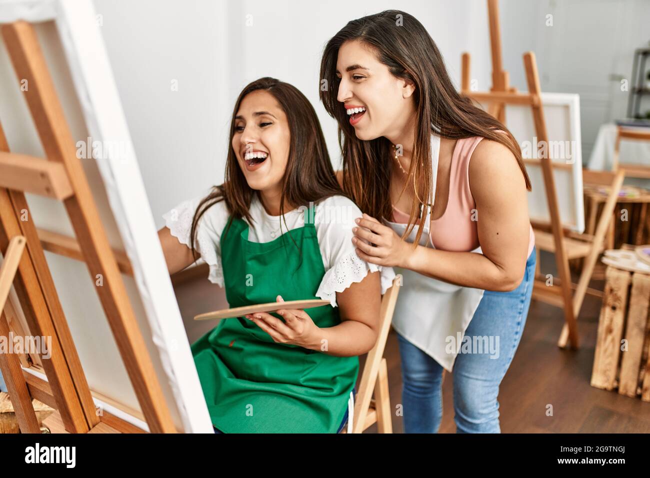 Student and teacher smiling happy painting at art school Stock Photo ...