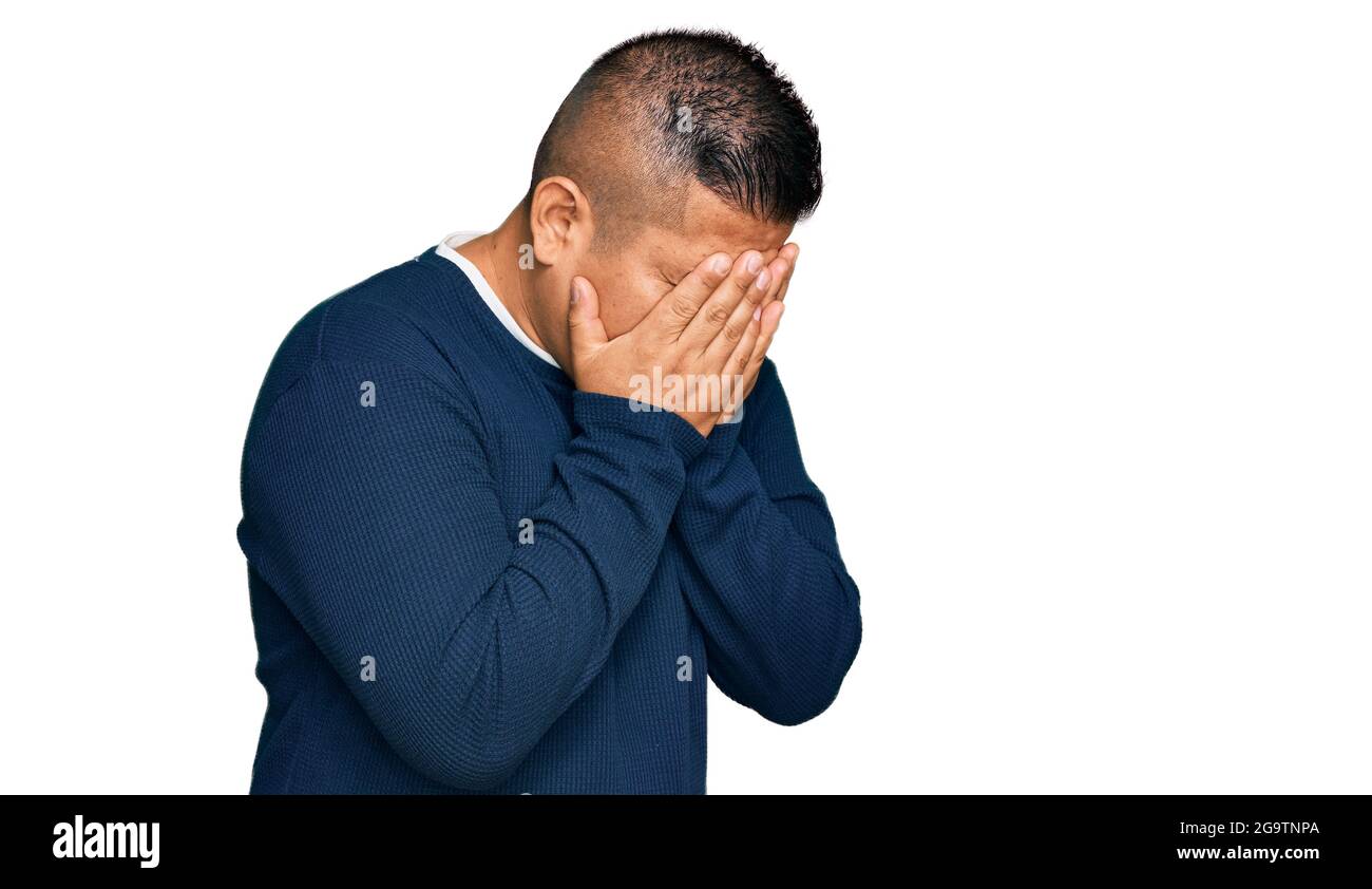 Young latin man wearing casual clothes with sad expression covering ...