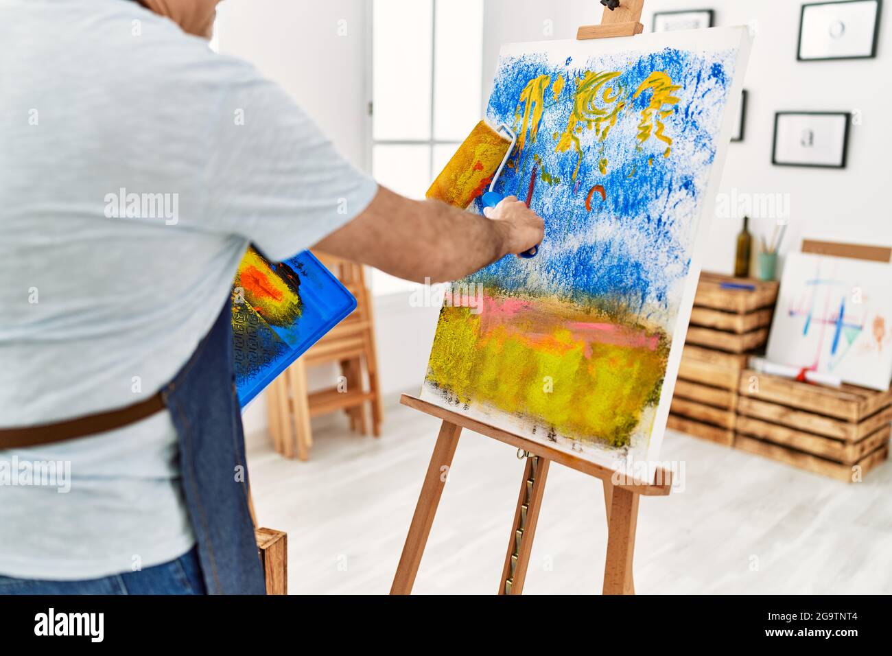 Painter man painting using paint roller at art studio Stock Photo - Alamy