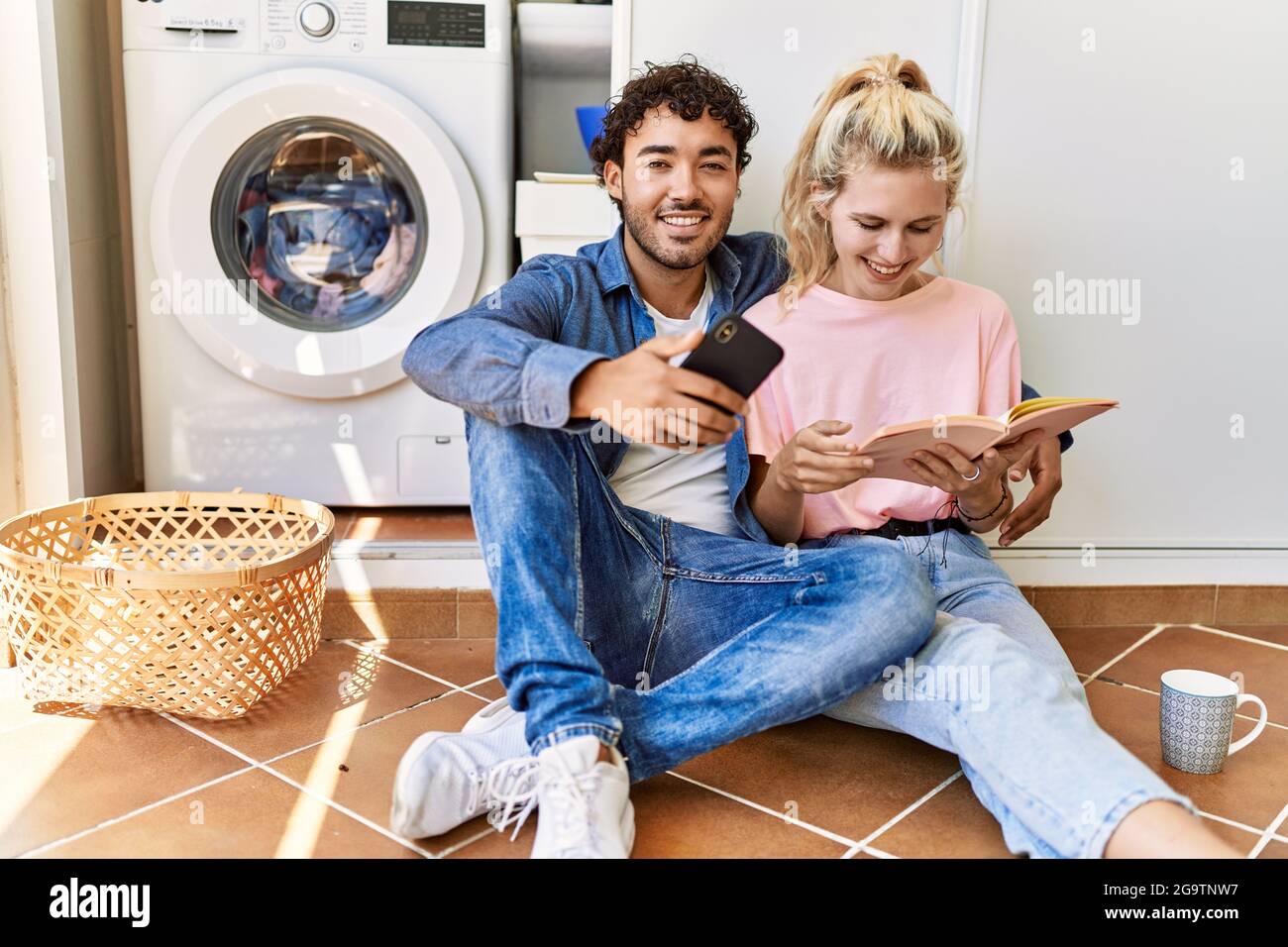 Young couple smiling happy reading book and using smartphone while ...