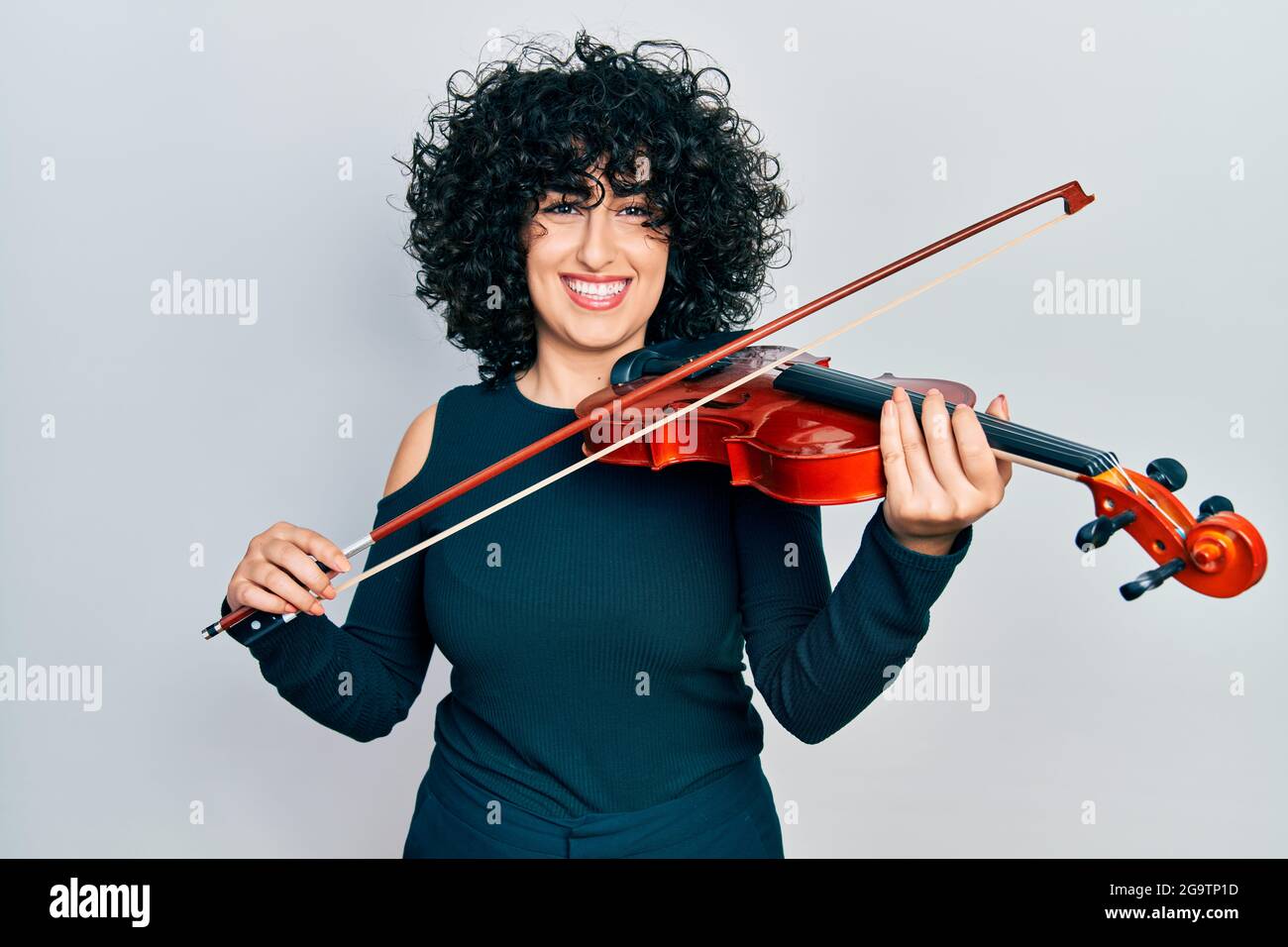 Young middle east woman playing violin smiling with a happy and cool ...