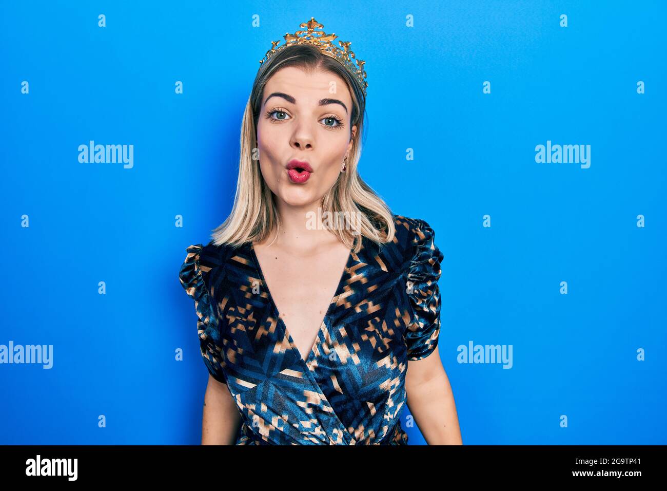 Beautiful caucasian woman wearing princess crown scared and amazed with ...
