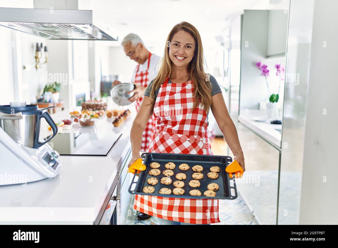 Middle age hispanic couple smiling happy baking cookies at the kitchen ...