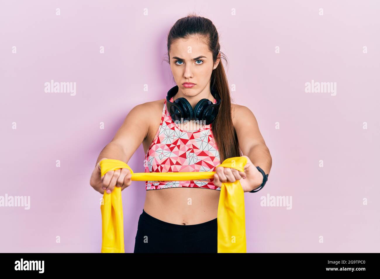 Young brunette teenager training arm resistance with elastic arm bands ...
