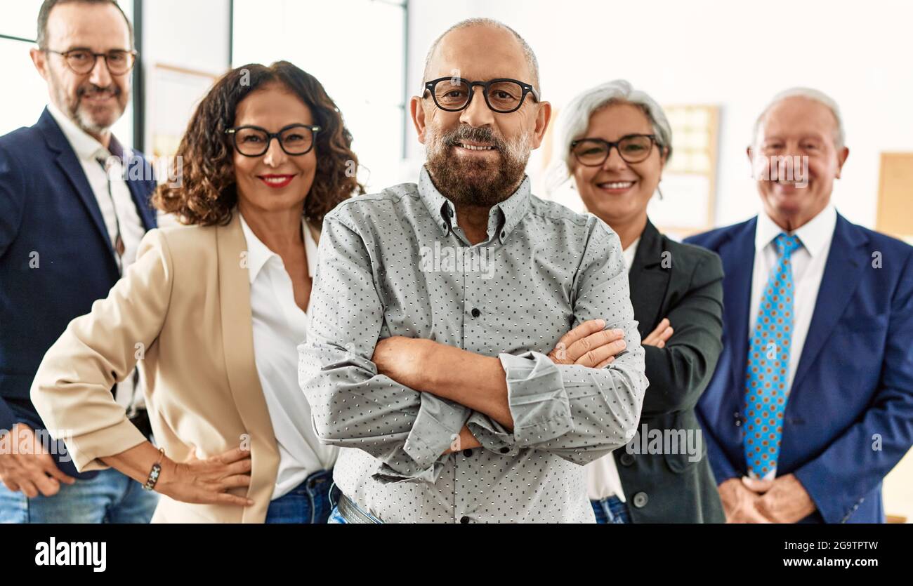Group of middle age business workers smiling happy standing with arms ...