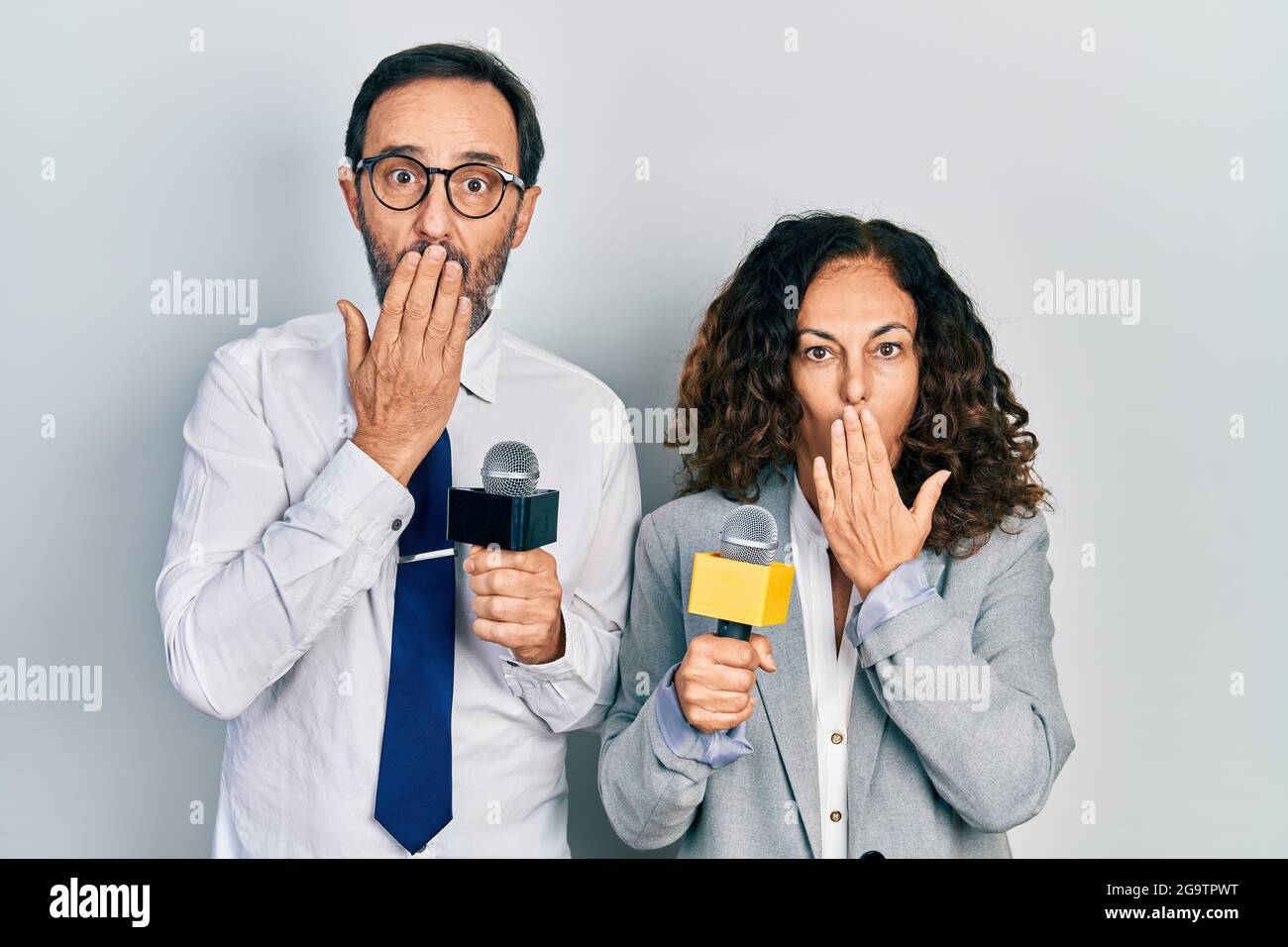 Middle age couple of hispanic woman and man holding reporter ...