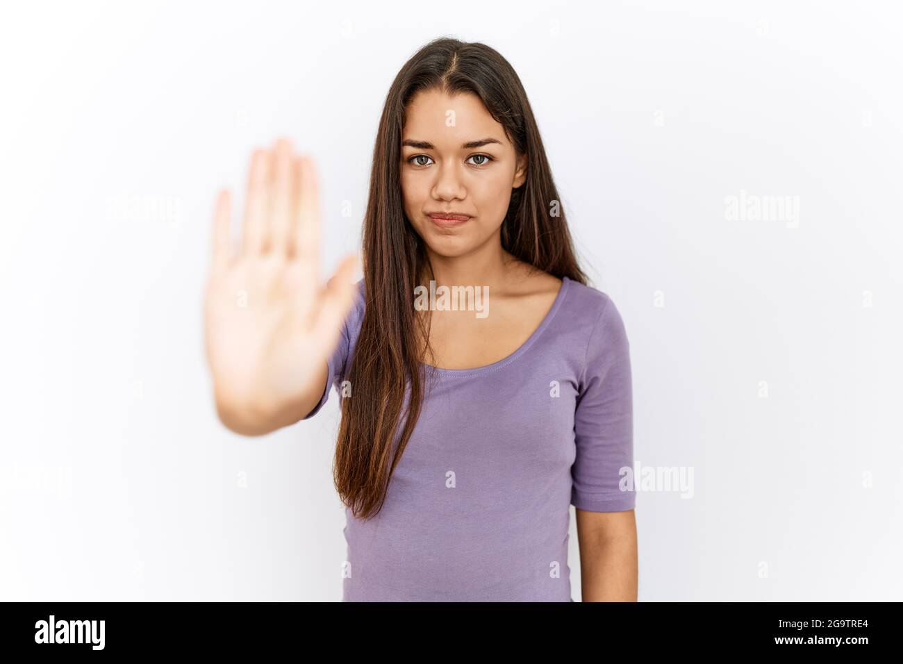 Young brunette woman standing by isolated background doing stop sing ...