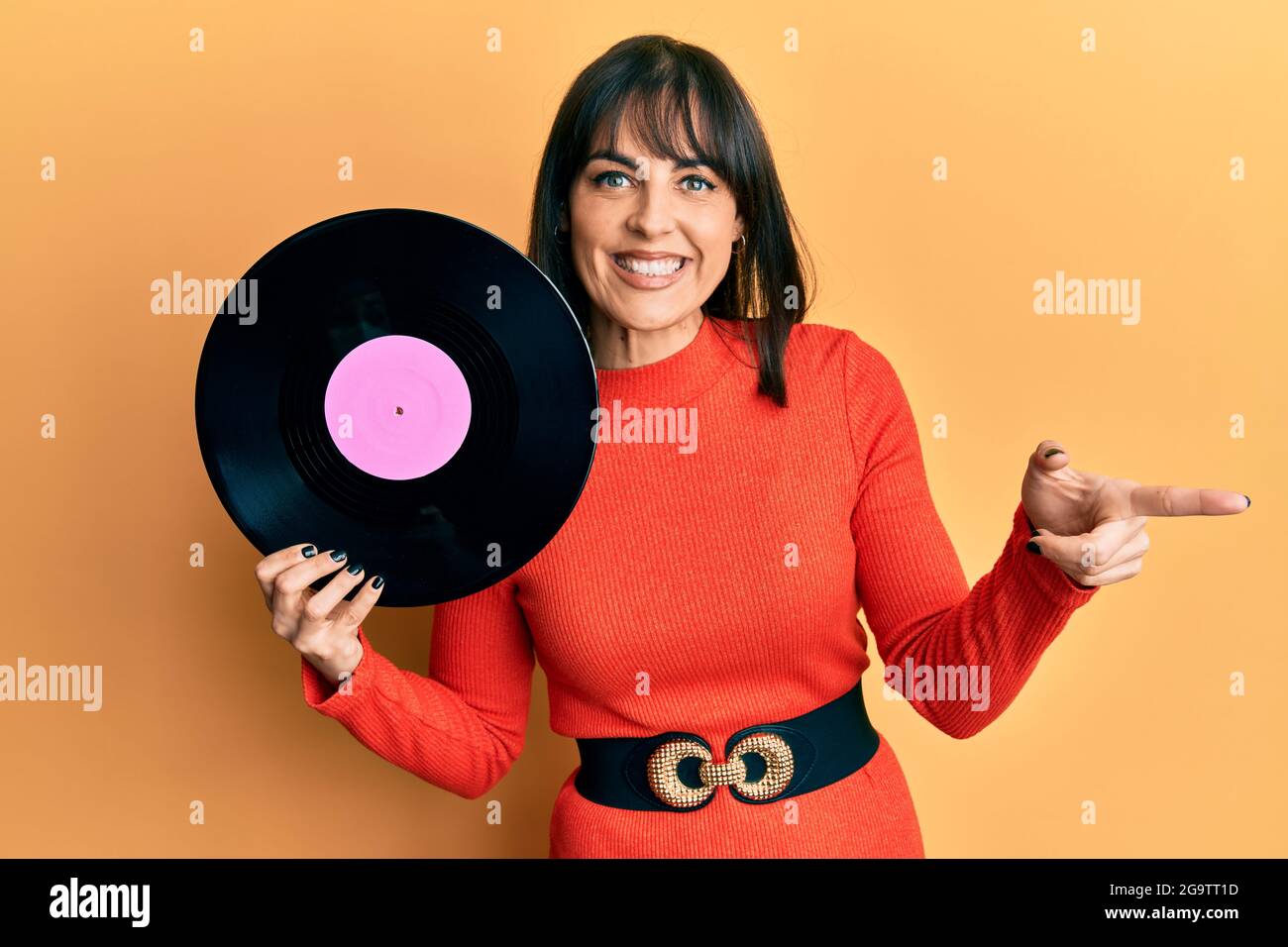 Young hispanic woman holding vinyl disc smiling happy pointing with ...