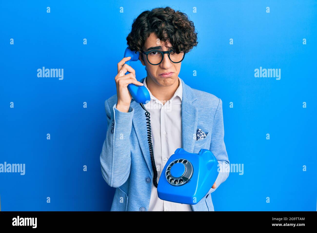 Hispanic young man speaking on vintage telephone depressed and worry ...