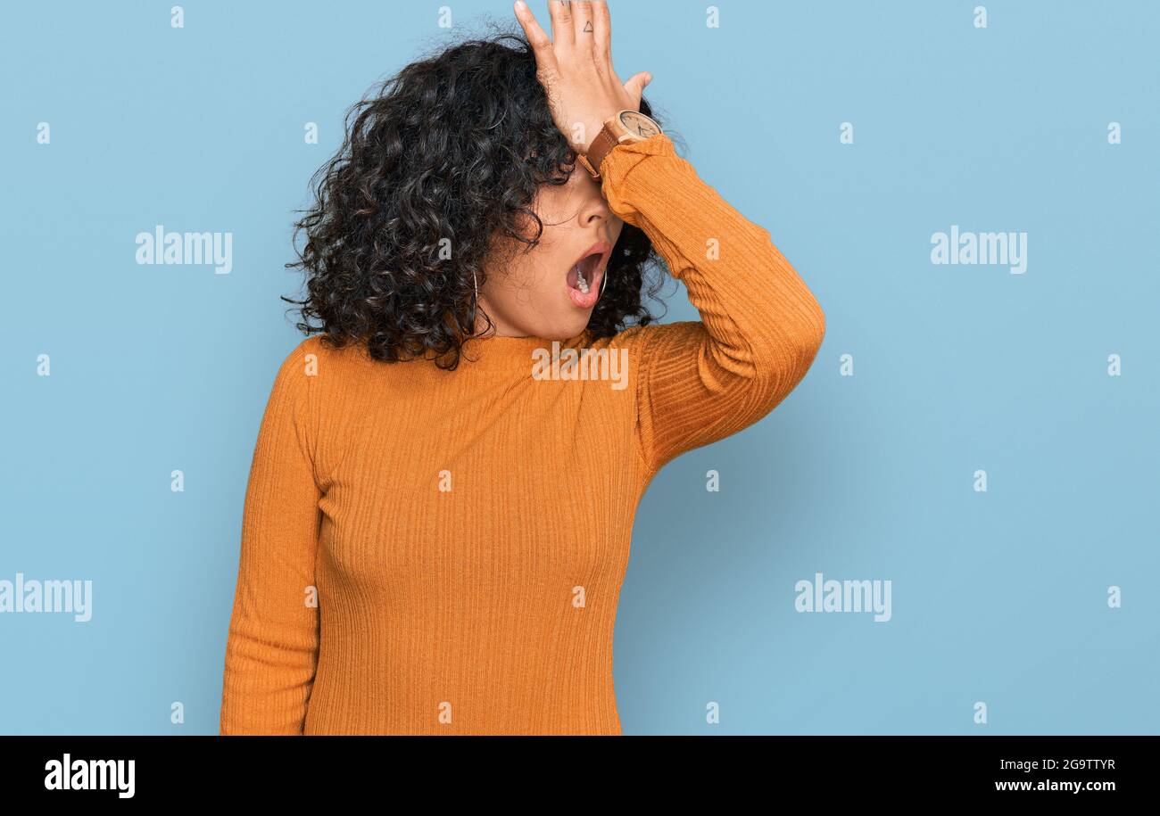 Young hispanic woman wearing casual clothes surprised with hand on head ...