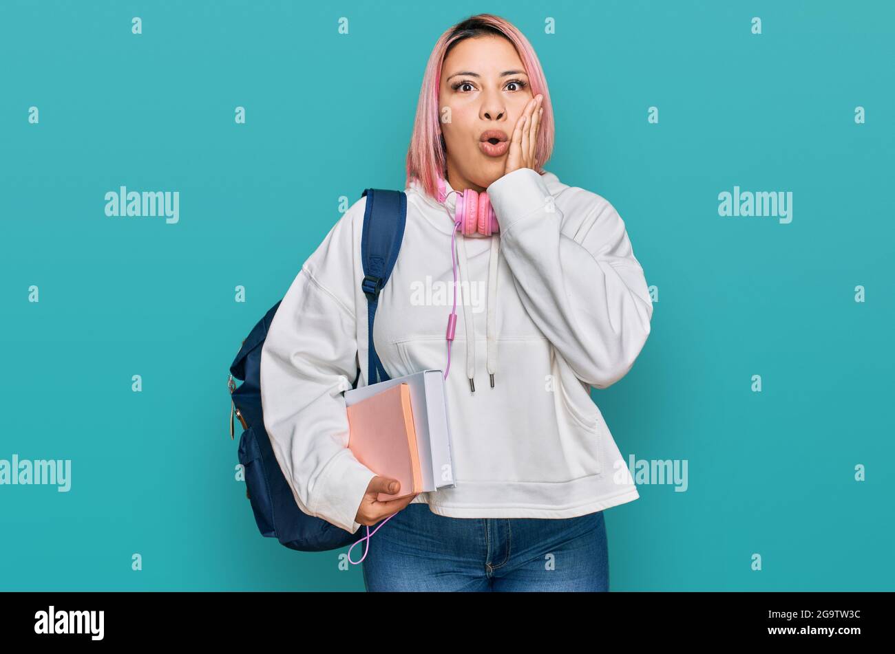 Hispanic woman with pink hair wearing student backpack and headphones ...