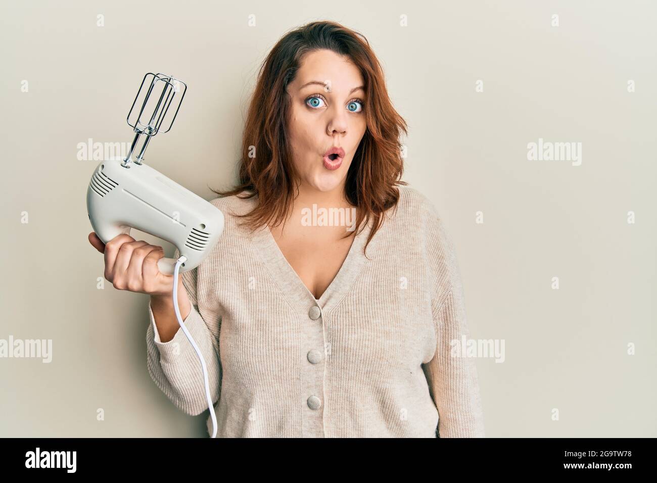 Young caucasian woman holding food processor mixer machine scared and ...