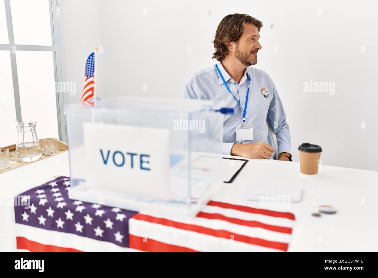 Handsome middle age man sitting at voting stand looking to side, relax ...