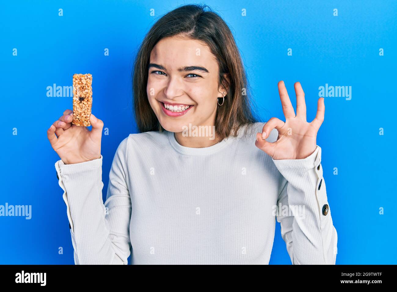 Young caucasian girl eating protein bar as healthy energy snack doing ...