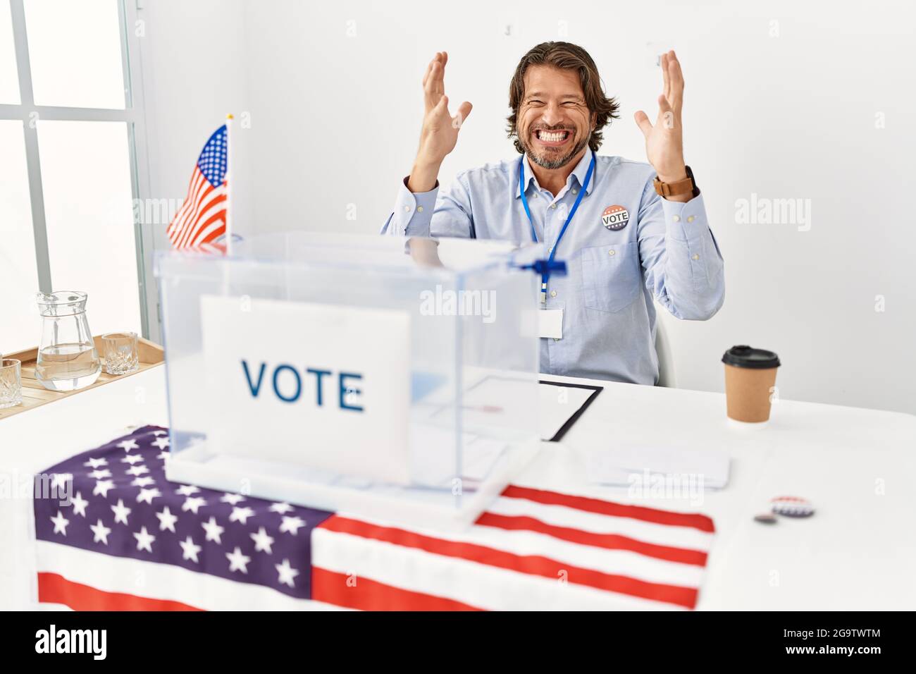 Handsome middle age man sitting at voting stand celebrating mad and ...